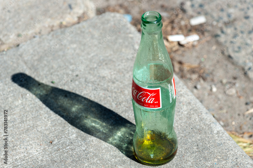 empty glass bottle of Coca-Cola on a concrete surface with shadow ...