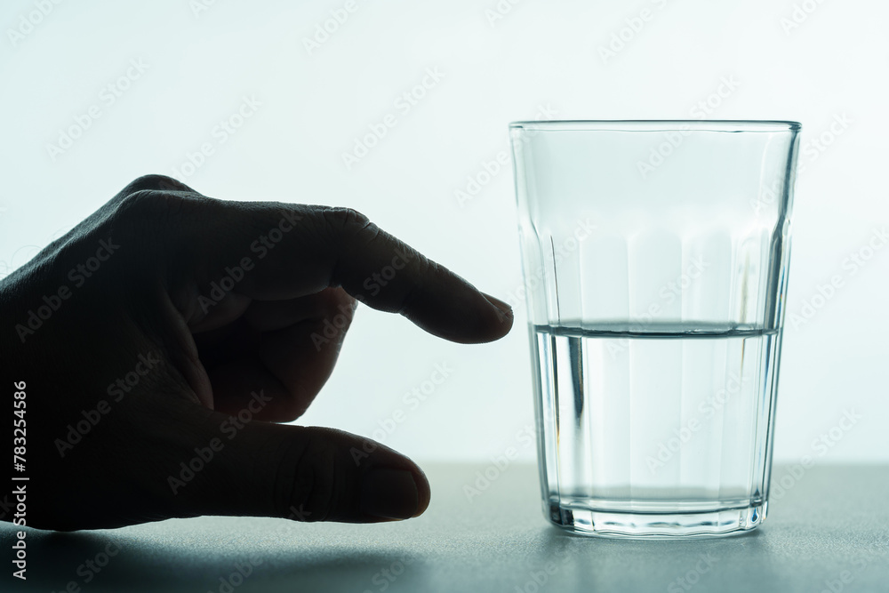 A glass half full of water concept, with a hand showing the part of a ...