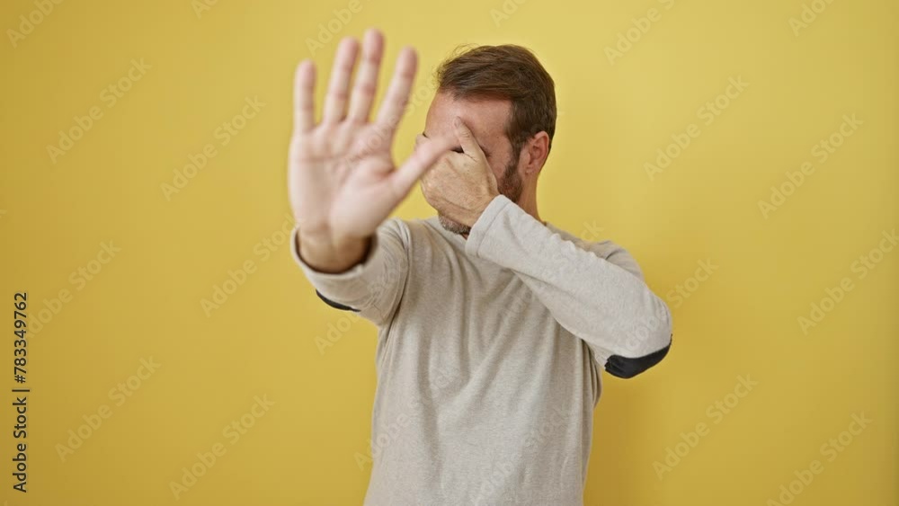 Terrified hispanic man fearfully covering eyes with hands, making stop ...
