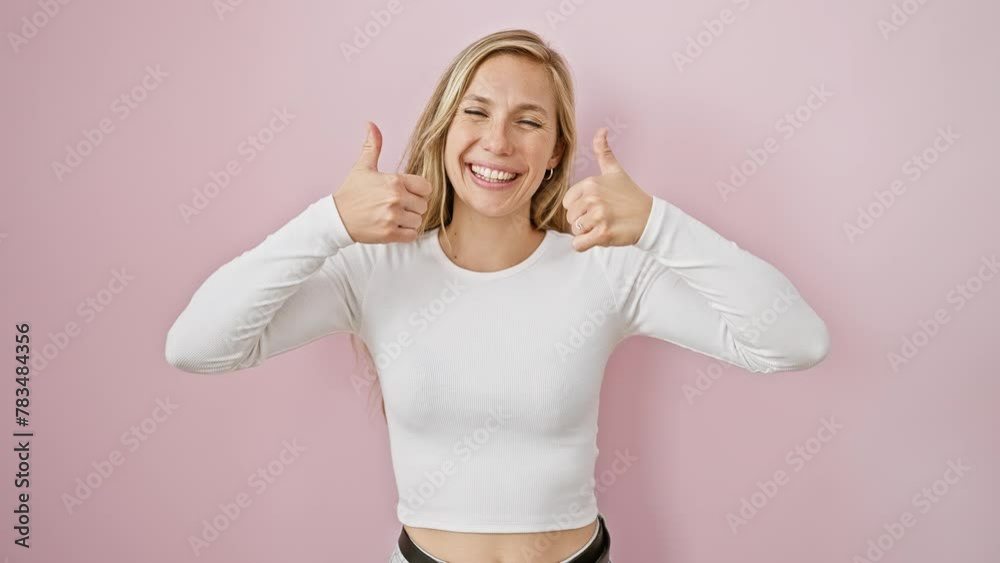 Joyful and successful young blonde woman standing, flashing a thumbs up ...