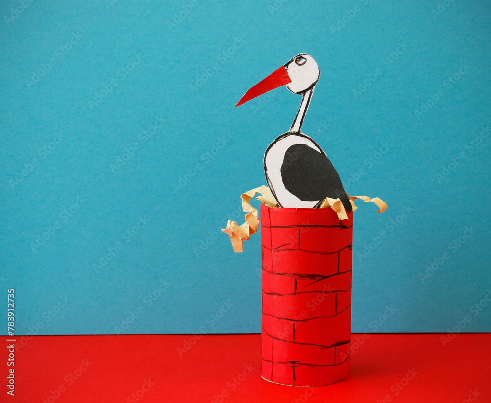A stork sitting in a nest on a chimney made by a child from a roll of ...