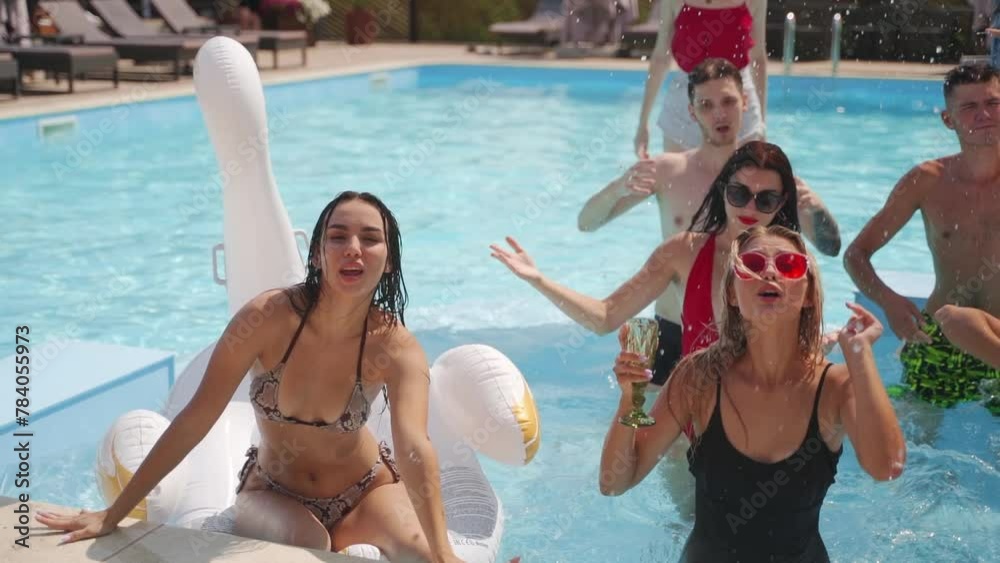 Female and male models chilling in swimming pool, splashing water, flirting and posing for ...