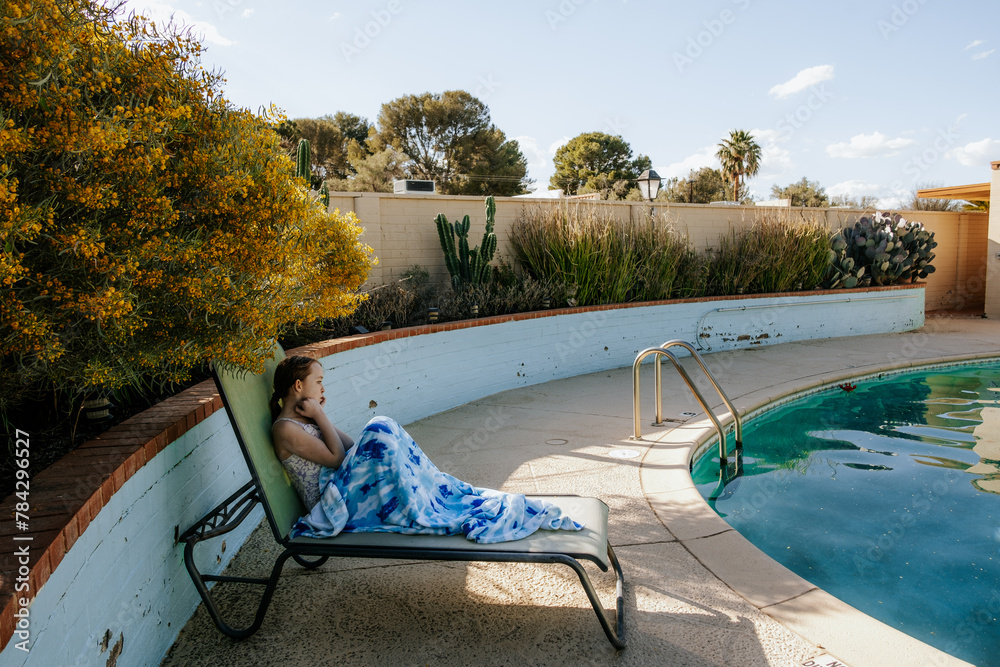 Tween girl sitting in lounge chair near pool on sunny day Stock Photo ...