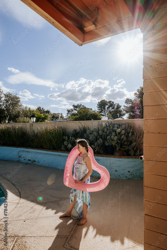Tween girl standing near pool holding float Stock Photo | Adobe Stock