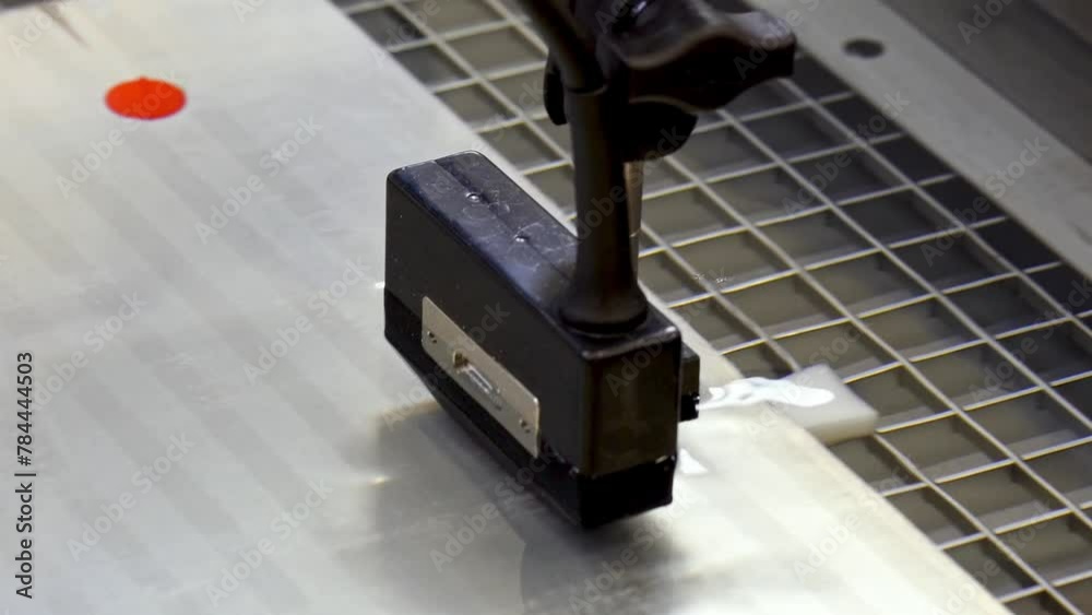 A close-up view of an industrial tool measuring a metal plate in a ...