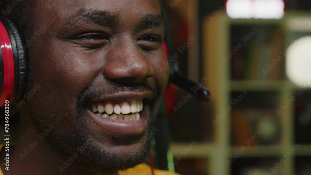 Closeup of gen z Black male gamer speaking with team players through ...