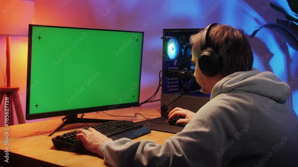 Computer with chroma key green screen on monitor. Gamer man playing in ...