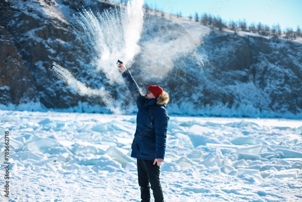 Man in blue jacket pours boiling water from a thermos that turns into a ...