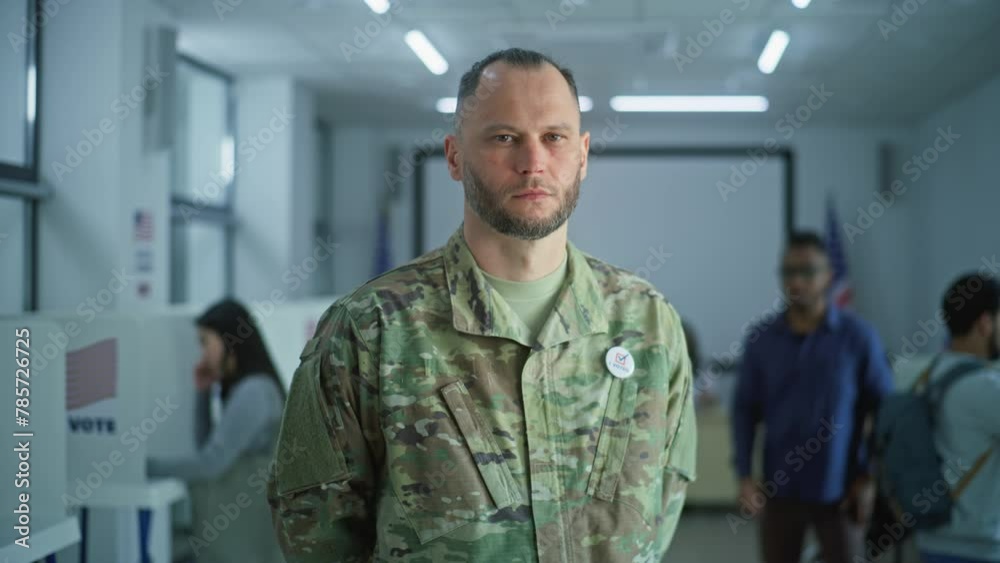 Man in camouflage uniform stands in a modern polling station and looks ...