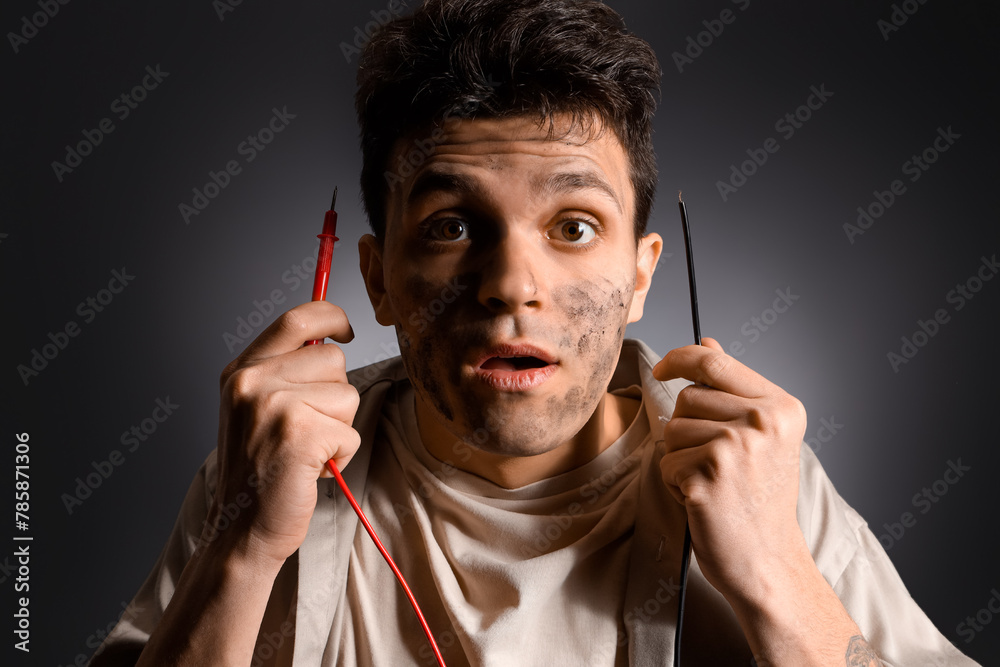 Electrocuted young man with burnt face and wires on dark background ...