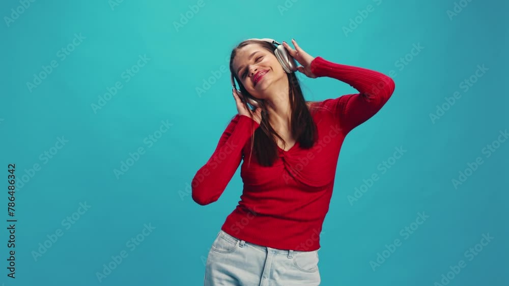 Young positive, smiling, happy girl listening to music in headphones ...