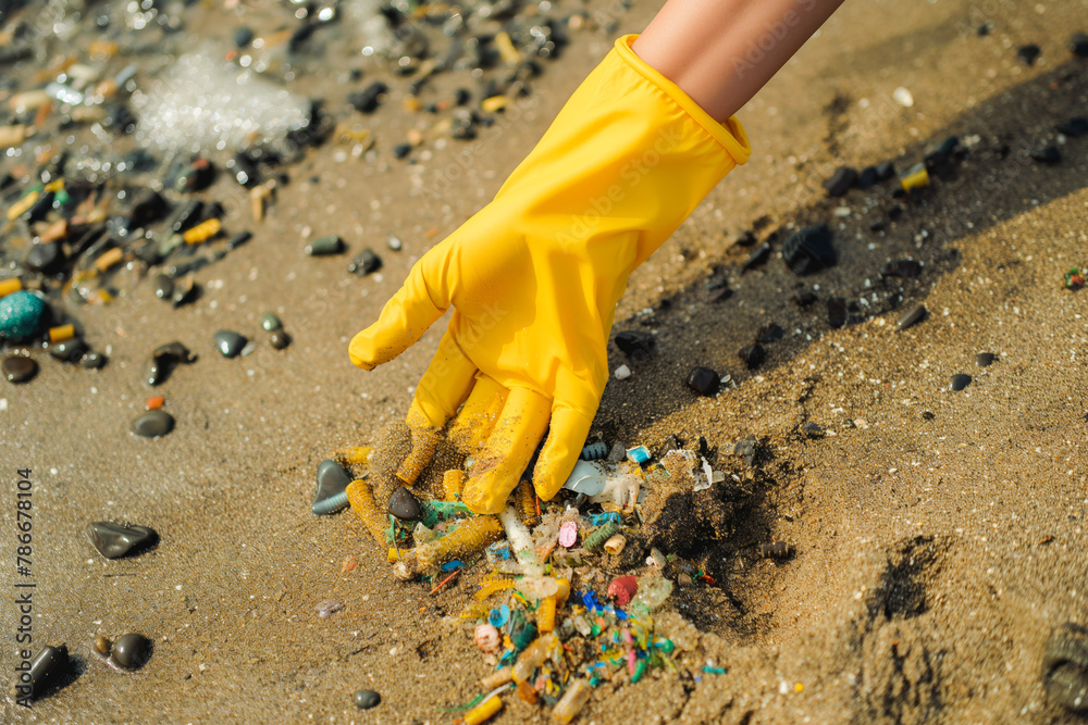 Volunteer hand with yellow gloves collect micro plastics collects ...