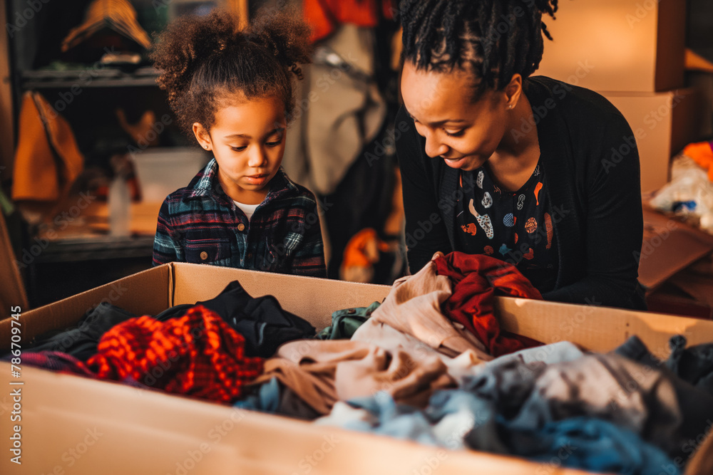 Woman and child sorting clothes and packing into cardboard box ...