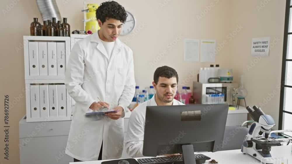 Two men in lab coats working together in a bright laboratory, one ...