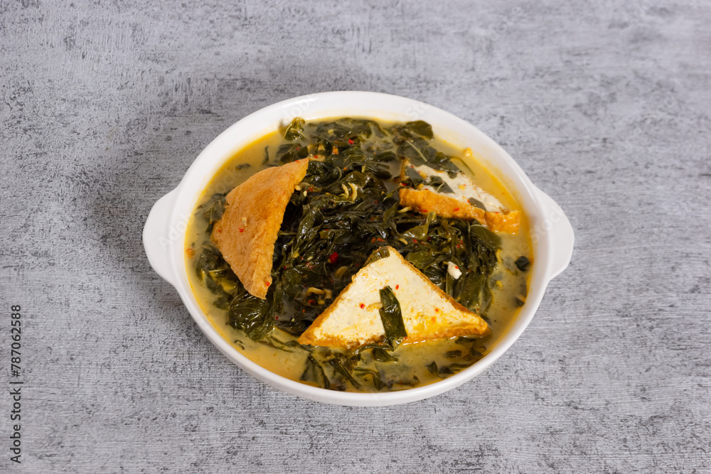 Gulai Daun Singkong, or cassava leaf curry, is made by cooking cassava ...