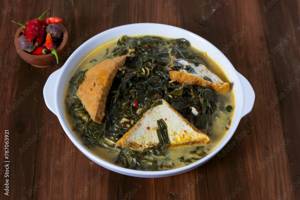 Gulai Daun Singkong, or cassava leaf curry, is made by cooking cassava ...