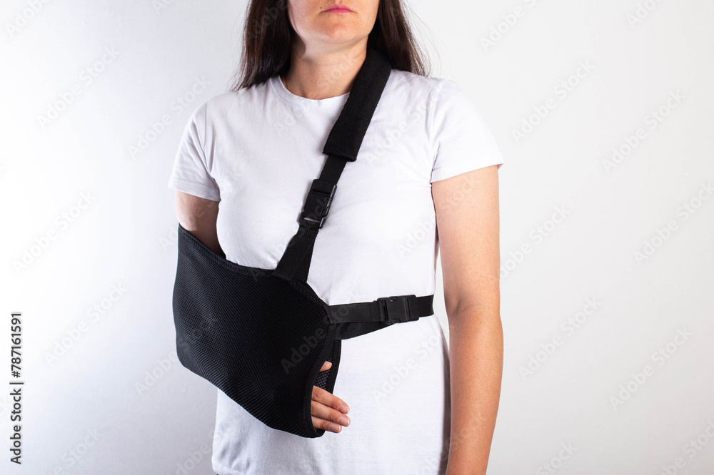A girl on a white background with a black supporting medical bandage ...