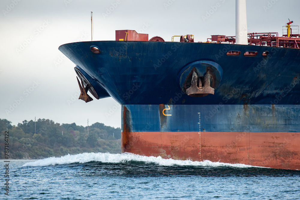 Big blue container ships bow with rusty anchors pushes a giant bow wave ...
