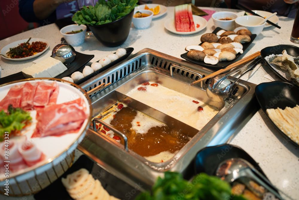 A square-sized Chinese hotpot bubbles with savory broth, inviting ...