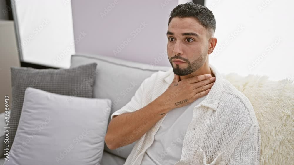 Pained expression on young arab man's face, sitting on sofa ...