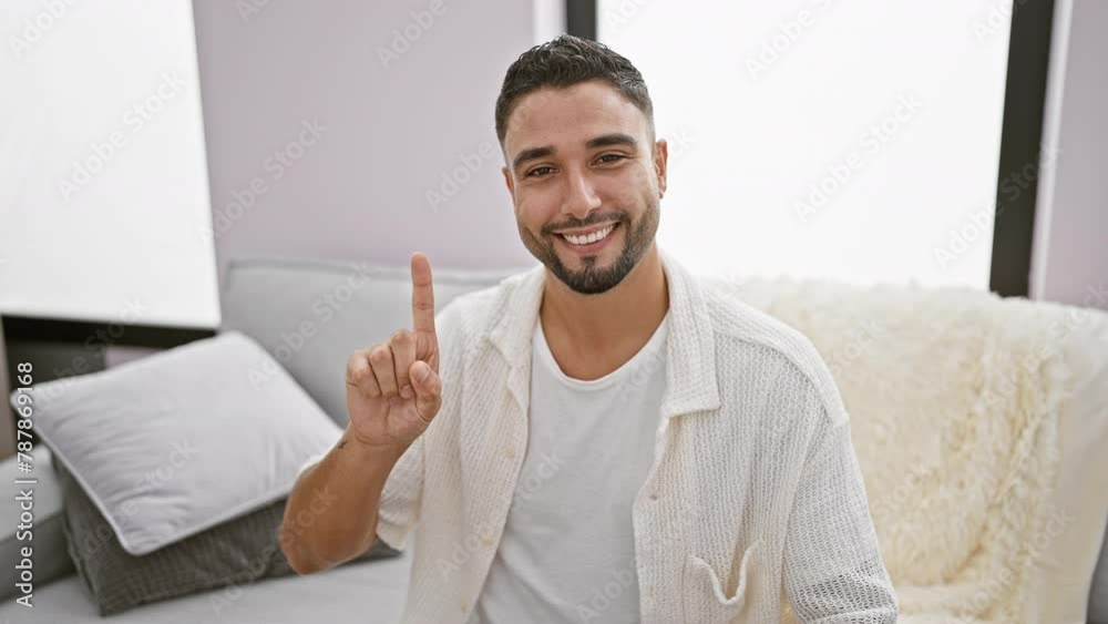 Cheers from home! charming young arab man joyfully pointing up number ...