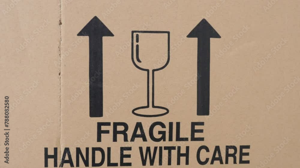 A close-up of a cardboard box. Reading fragile, handle with care sign ...