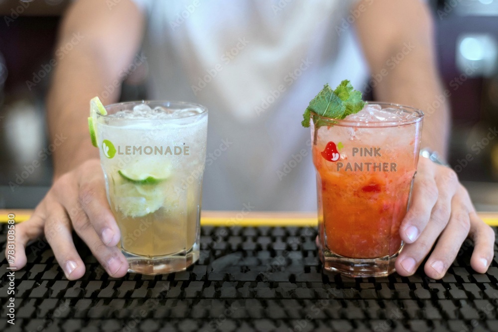 Two glasses, one filled with lemonade and the other with brilliant pink ...
