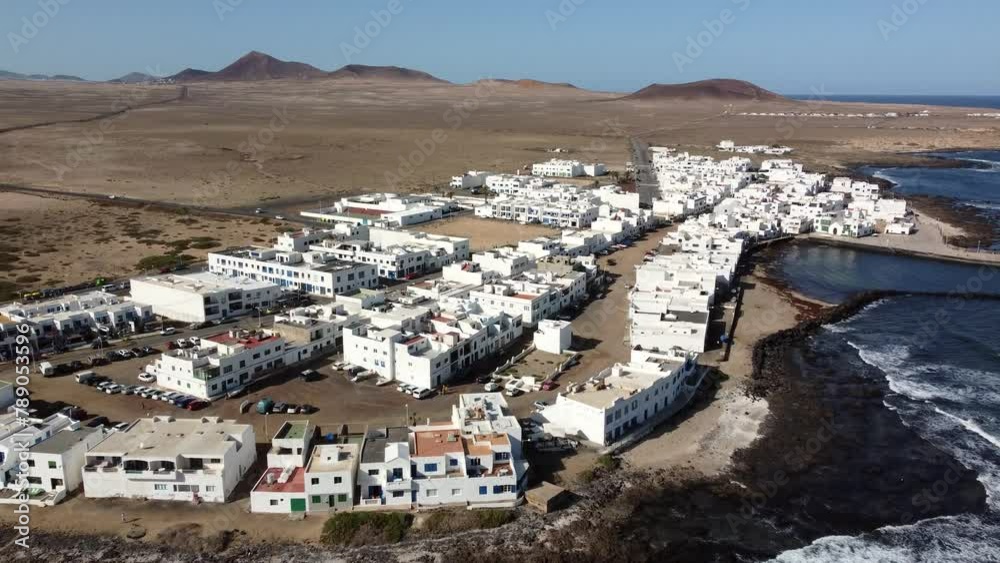 Aerial close up view of Caleta de Famara is town at mountain range ...