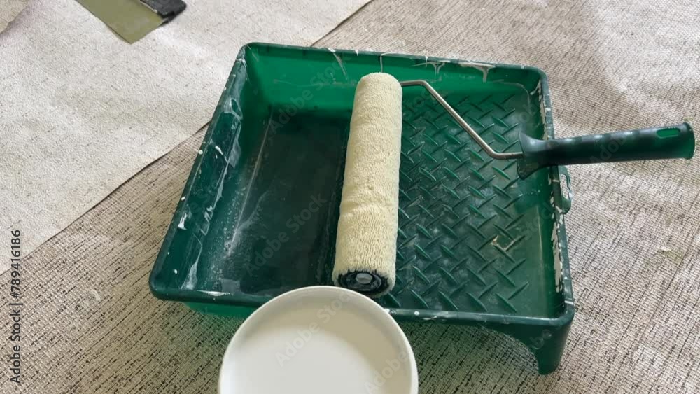 Paint roller with paint in container room. Painting the walls in a room ...