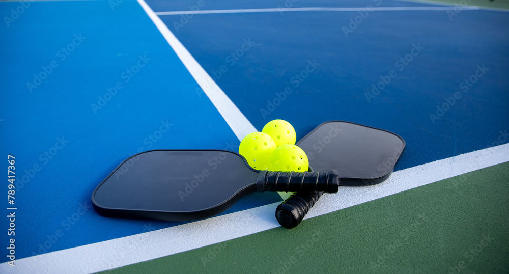 Pickleball paddles and balls on a game court. The sports equipment is ...