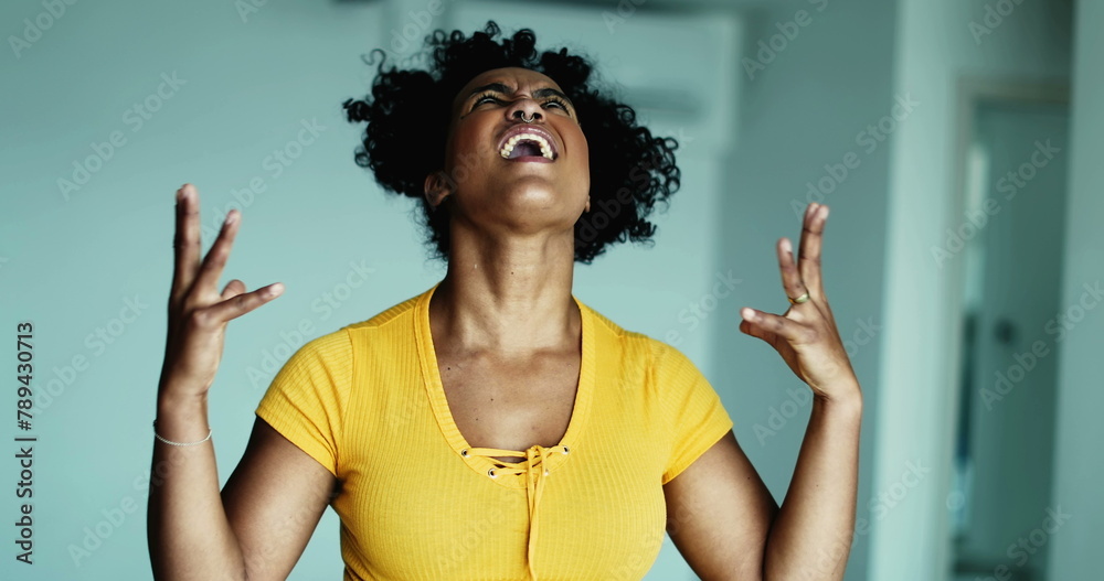 One frustrated young black woman screaming in despair at sky gesturing ...