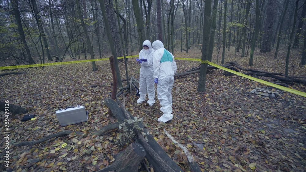 Forensic scientist examining a hazardous part of the forest wearing ...
