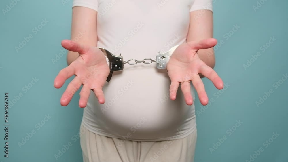 Pregnant woman in handcuffs, studio blue background. Concept of ...