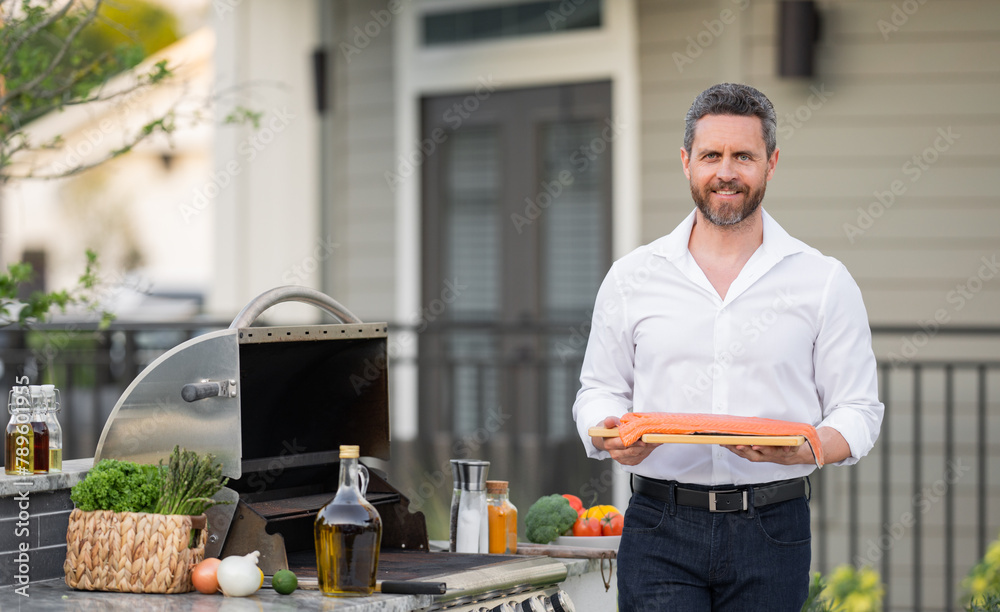 Male chef grilling and barbequing salmon fillet in garden. Barbecue ...