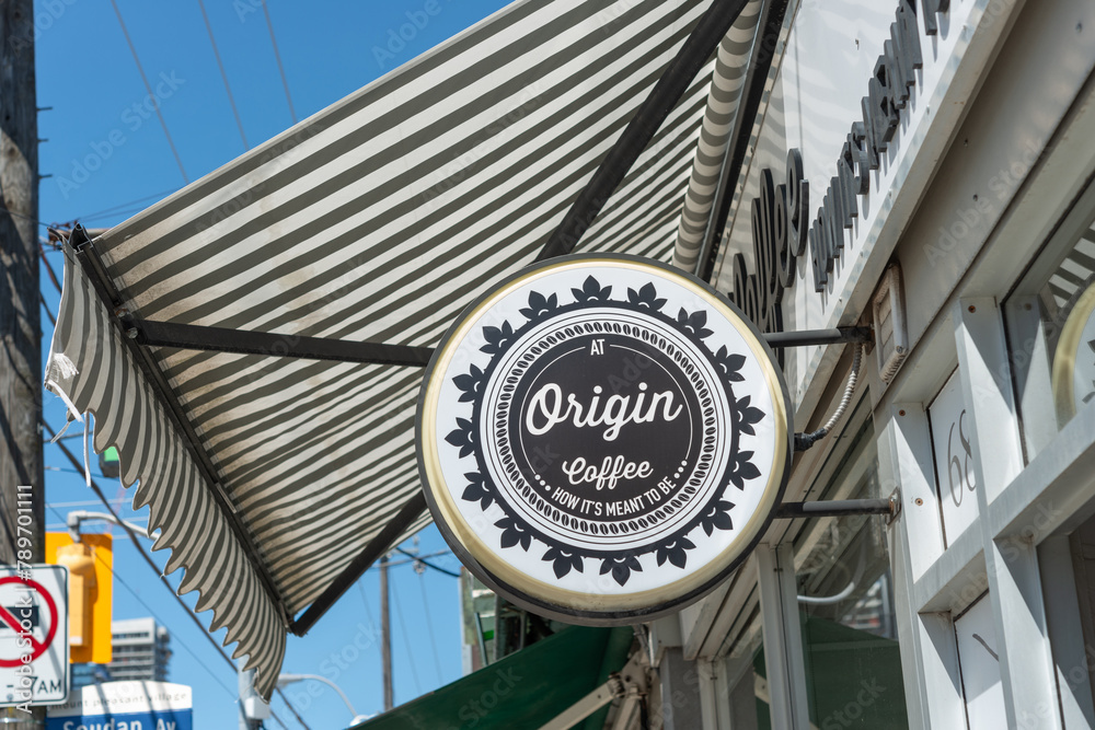 round projecting sign of At Origin Coffee, a coffee shop, with black ...