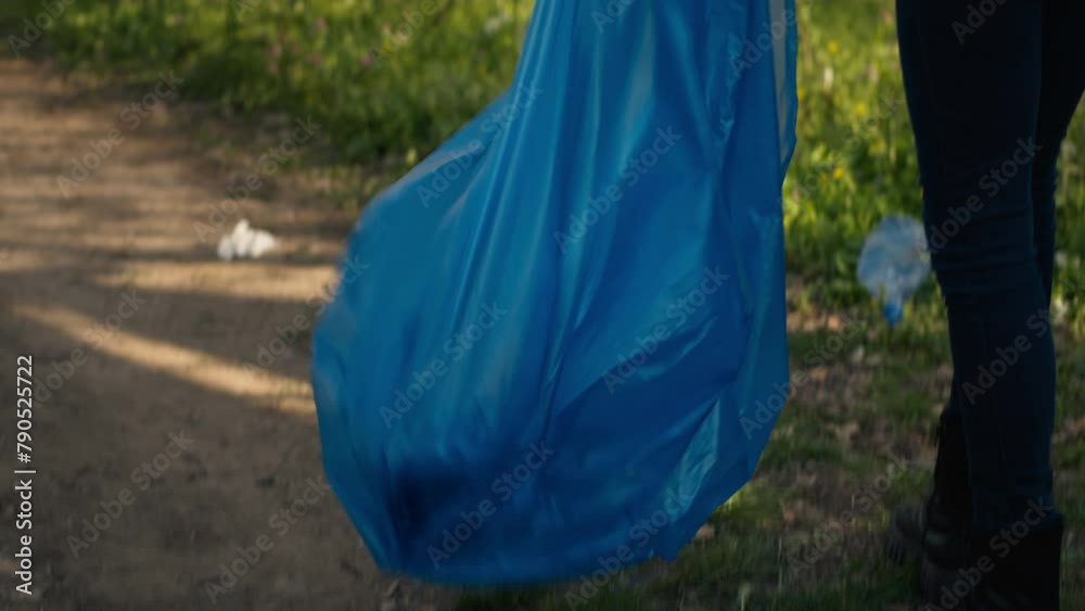 African american girl collecting rubbish in a trash bag using tongs ...