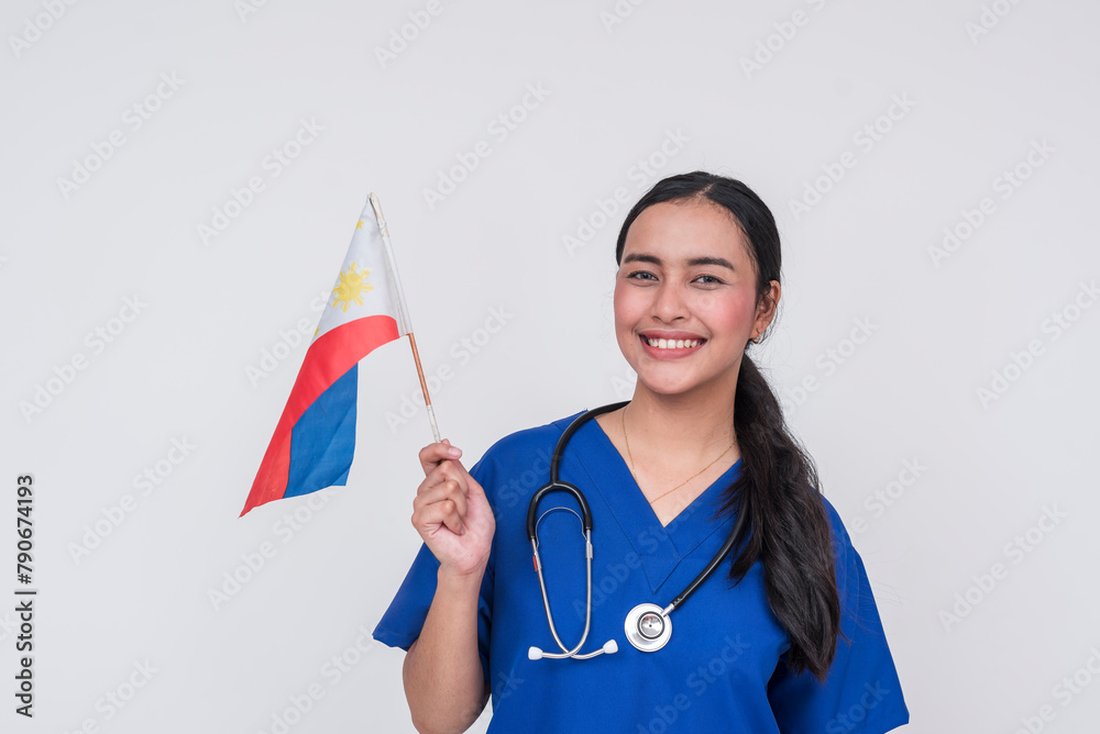 Proud Filipino nurse in blue scrubs holding a Philippine flag on a ...