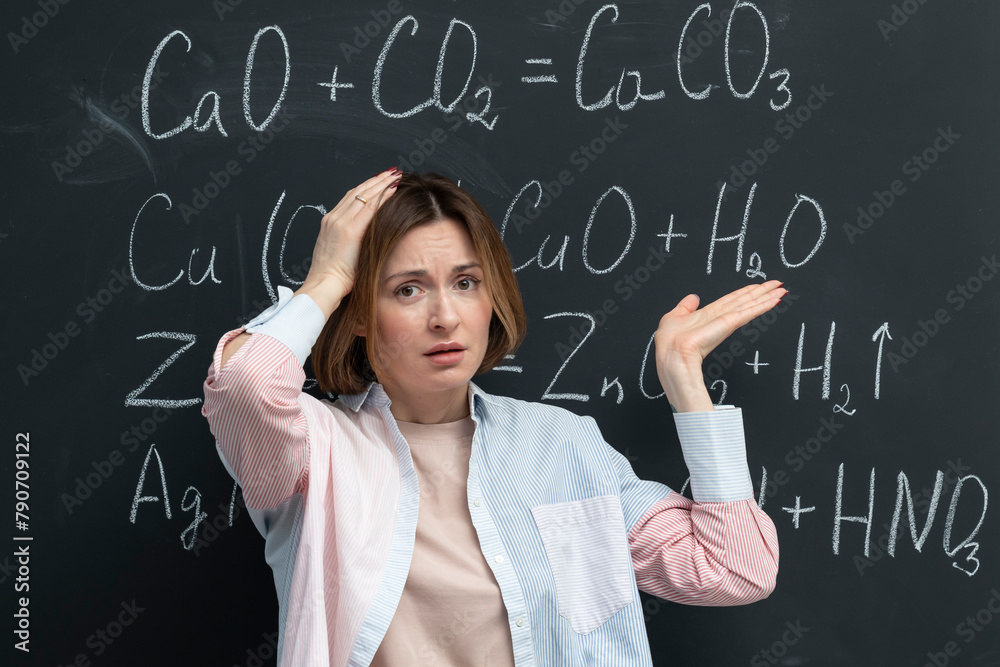 Confused female student writing the formula of a chemical reaction on ...