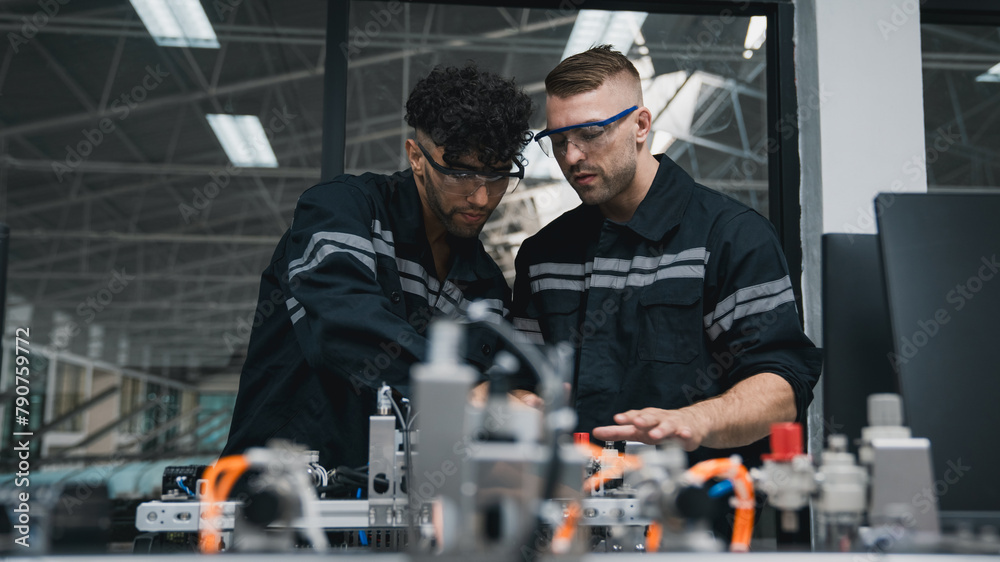 Engineering student assembling a robotic arm using a computer in a ...