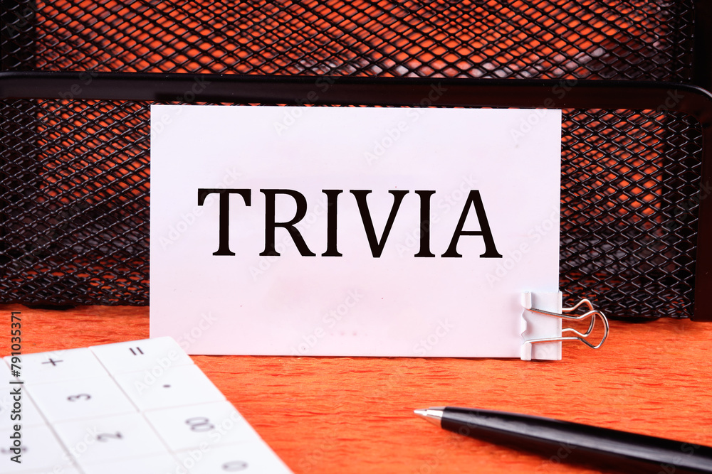 TRIVIA word on a clean white business card next to a calculator, a pen ...