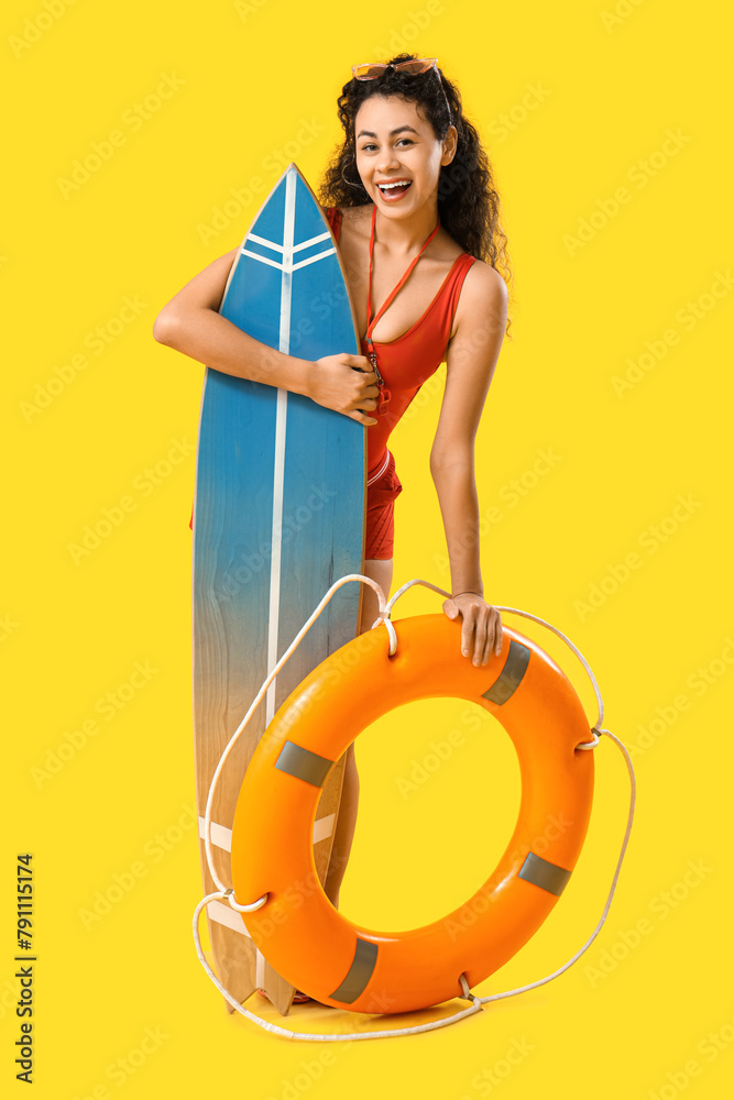 Beautiful young happy African-American female lifeguard with ring buoy ...