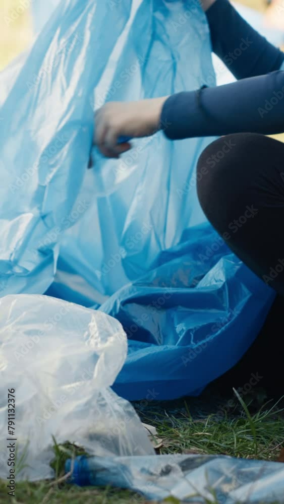 Tired little girl collecting trash and plastic bottles from the forest ...