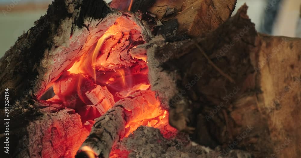 Glowing embers and flames within a charred wood log, exhibiting the ...