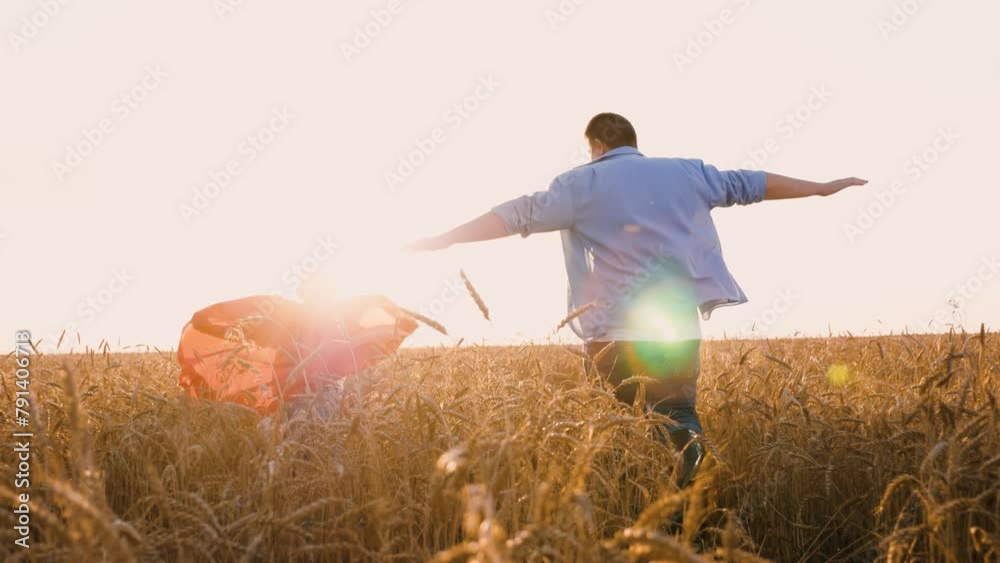 Father and son superhero in red cloak flying running at sunny dry wheat ...