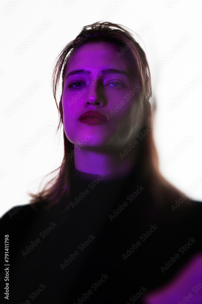 Beautiful young woman with purple illuminated face against white ...