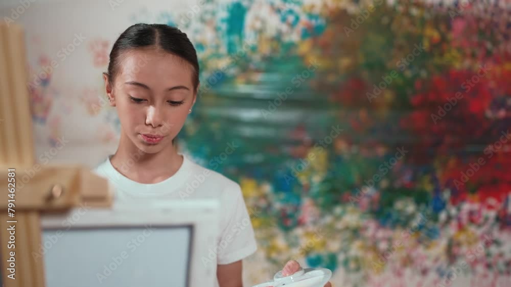 Pretty high school student painting canvas while standing at stained ...