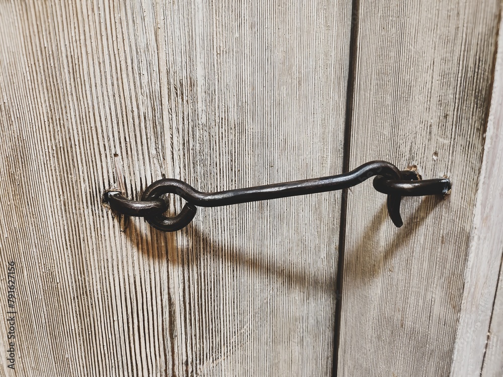 A rustic wooden door with a hand forged iron latch. The door is made of ...