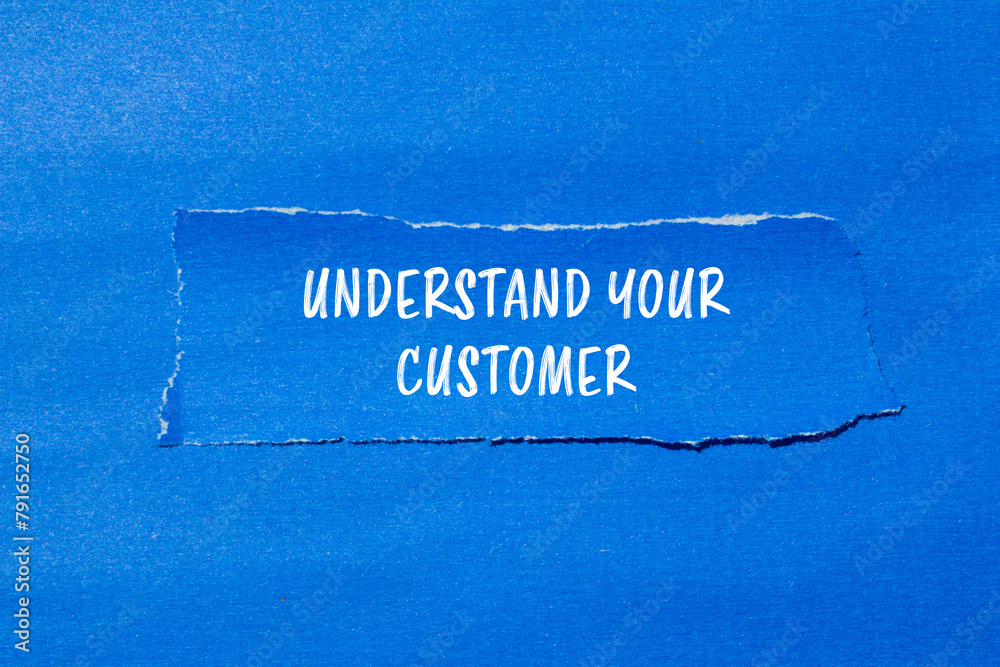 Understand your customer words written on ripped blue paper piece with ...