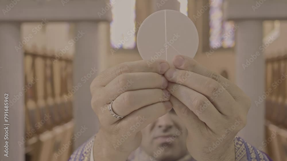 Priest lifting communion bread in church during Eucharist close up ...