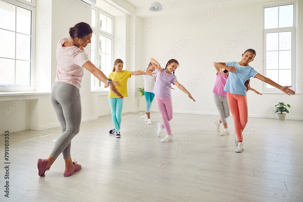 Smiling happy girls training modern dance moves together in studio with ...